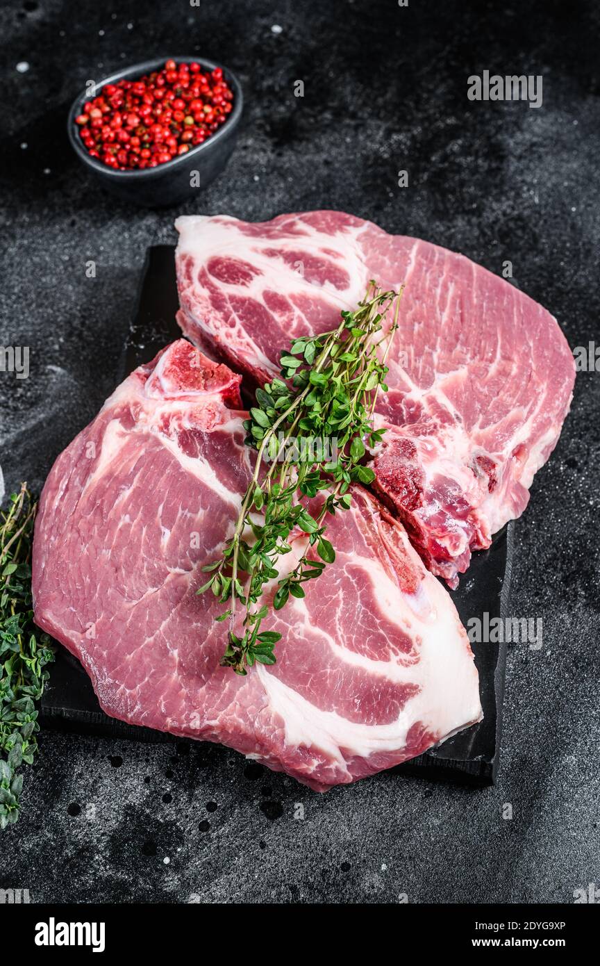Raw pork meat steaks on a marble board. Black background. Top view ...
