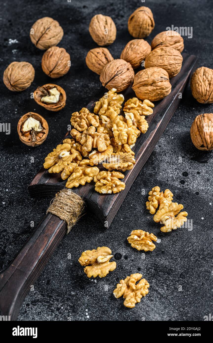 Shelled walnuts kernels on wooden cutting board. Black background. Top ...
