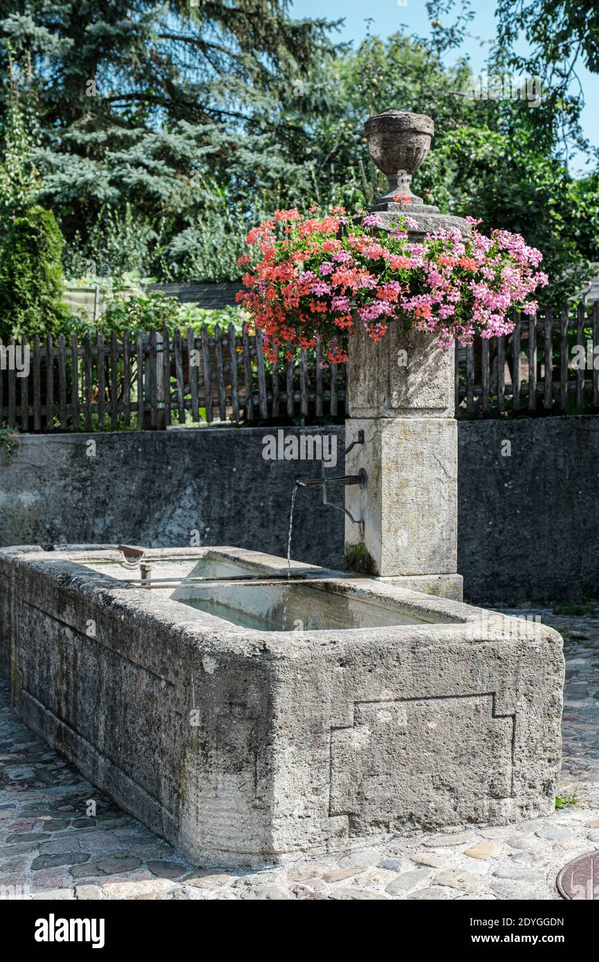 Traditional stone fountain with flowers located Stock Photo - Alamy