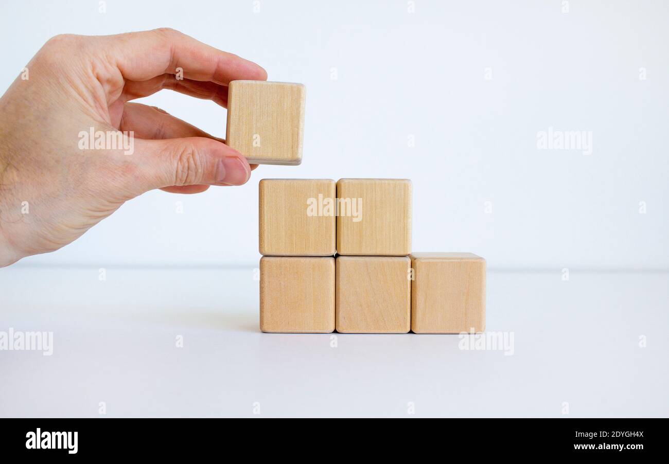 Symbol of building success foundation. Men hand put wooden cube on the ...