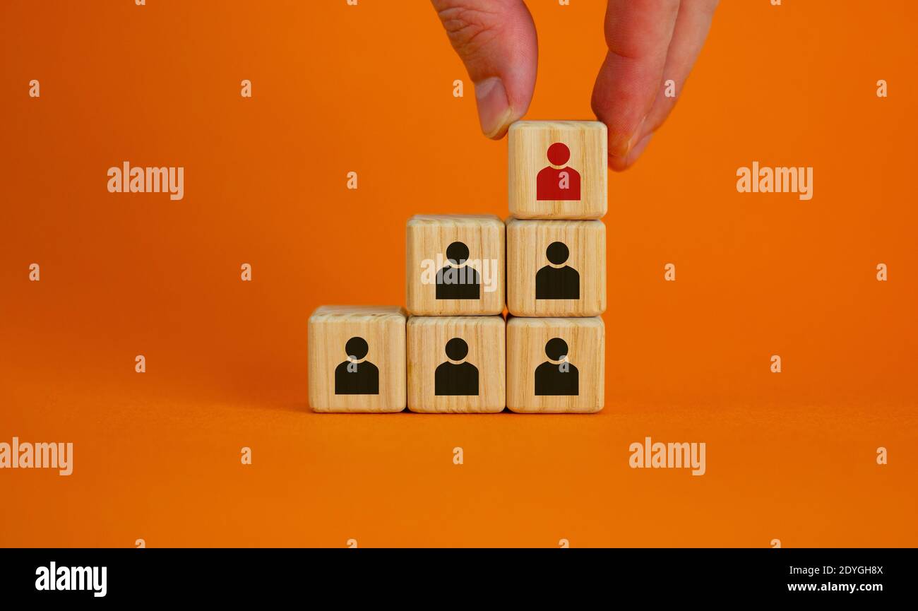 Business executive stacking wooden cubes with people icons on them in a ...