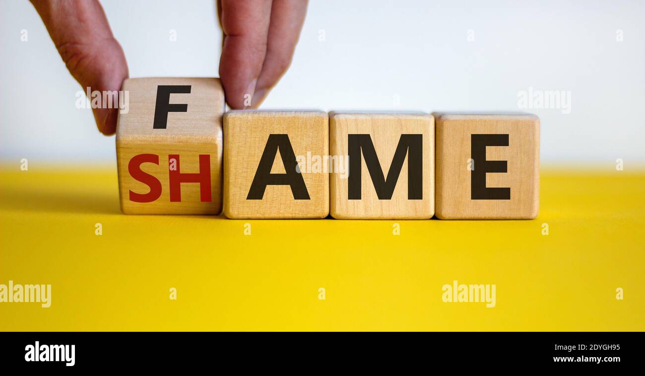 Fame or shame symbol. Male hand flips wooden cubes and changes the word ...