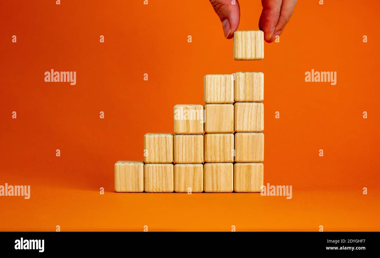 Symbol of building success foundation. Men hand put wooden cube on the ...