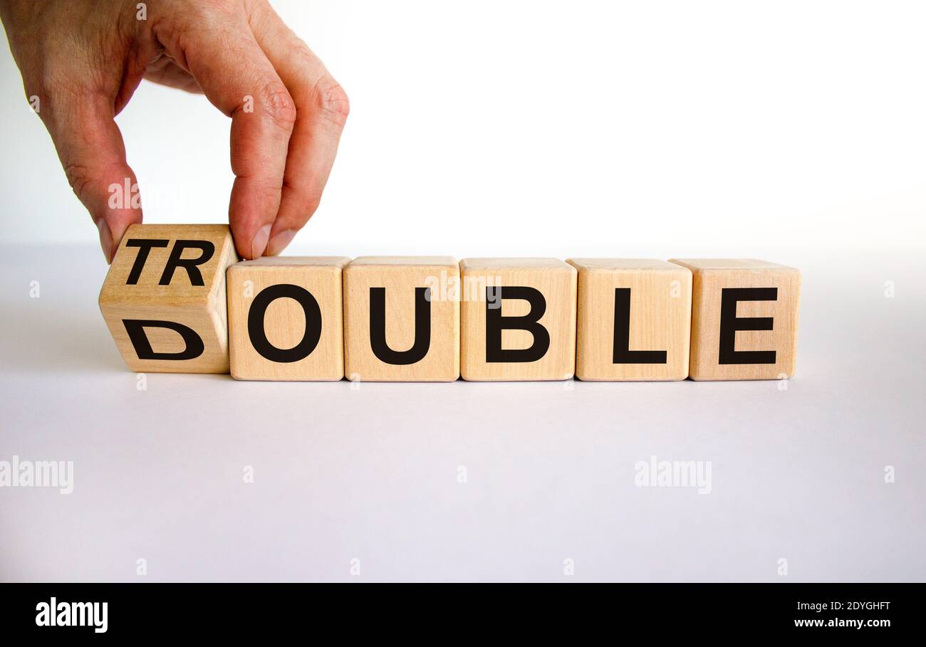 Double trouble symbol. Male hand flips a wooden cube with words 'Double ...