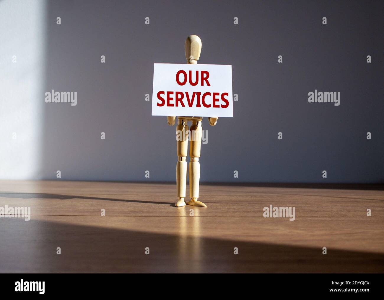Our services symbol. Wooden model of human holding a white paper with ...