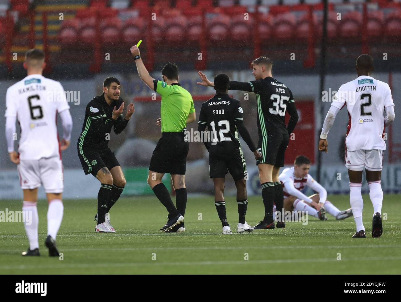 Match referee Don Robertson shows a yellow card to Celtic's Nir Bitton ...