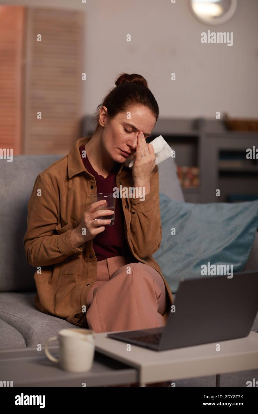 Depressed young woman crying while sitting on sofa and talking online ...