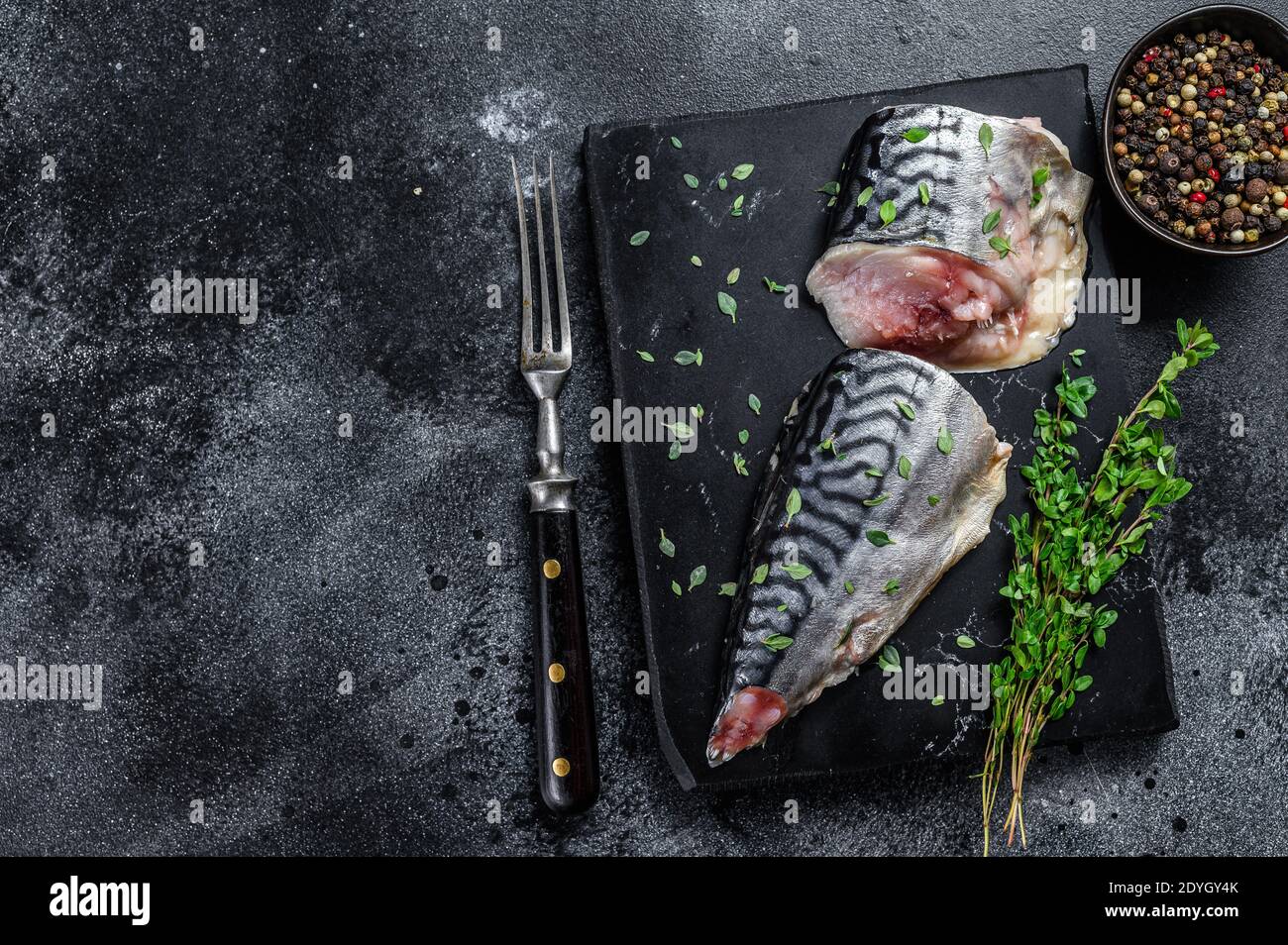 Cold smoked mackerel fish with herbs. Black background. Top view. Copy ...