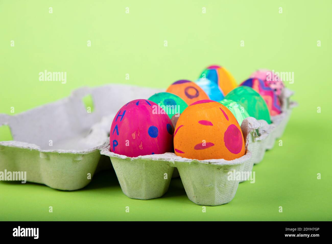 painted eggs with easter motives in an egg carton, green background ...