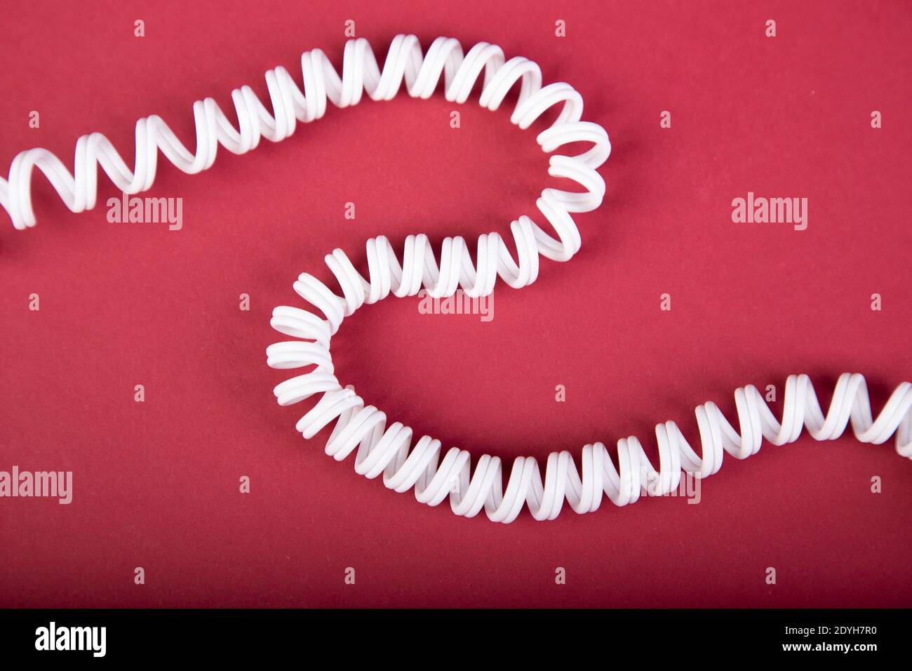 Coiled white wire runs through the picture, red background Stock Photo ...
