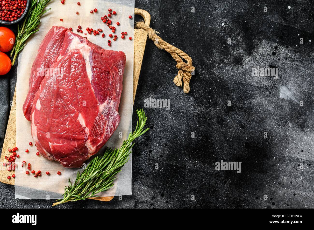 Raw Round beef cut on a cutting board. Black background. Top view. Copy ...