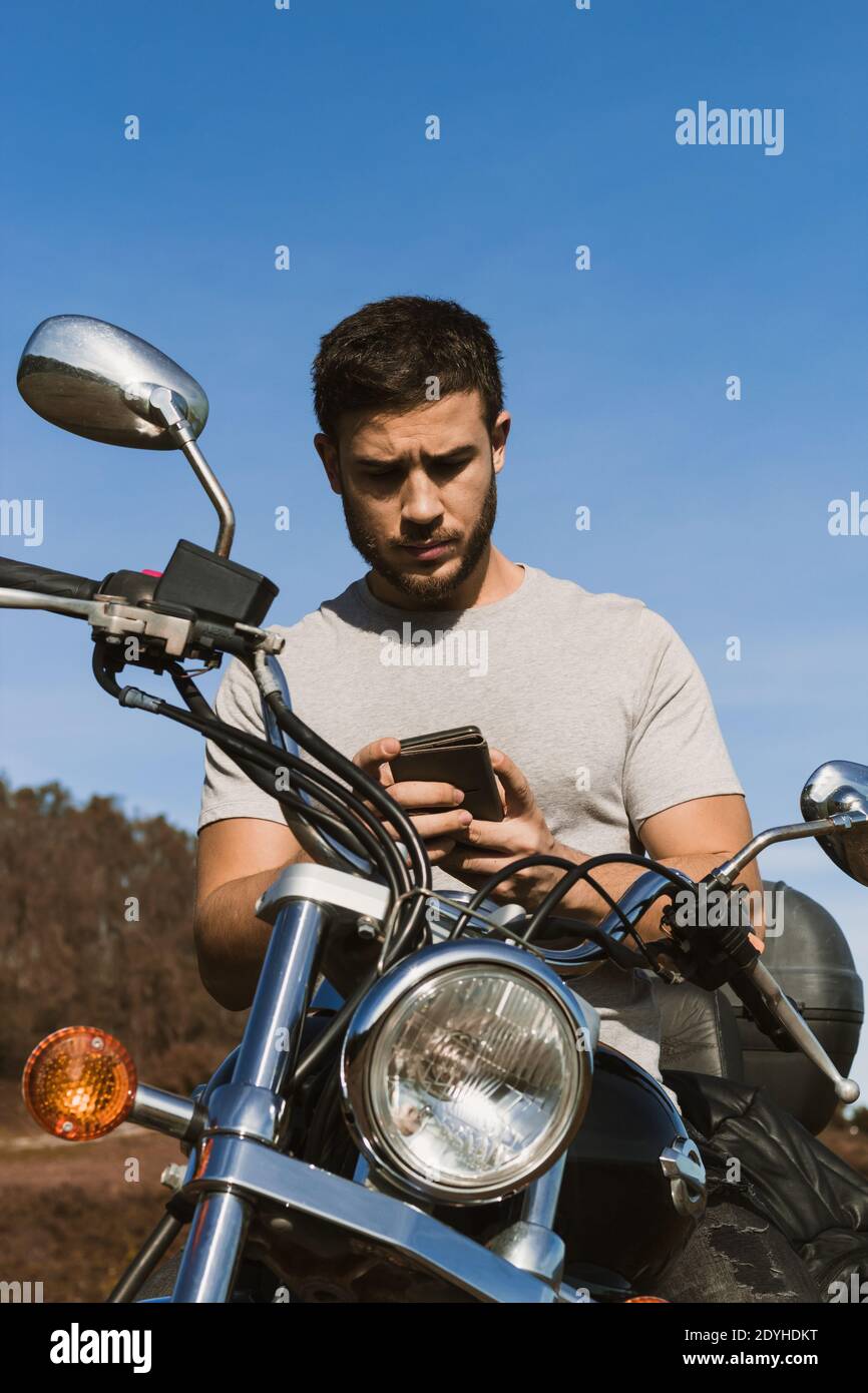 Biker looking at the mobile during a route Stock Photo - Alamy