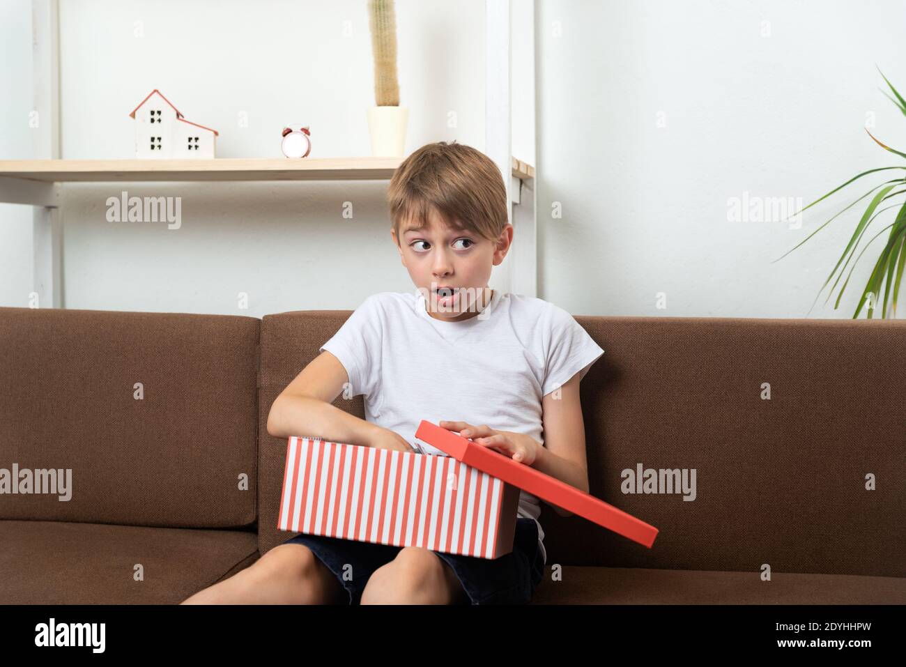 Surprised boy opens the gift box and looks around Stock Photo - Alamy
