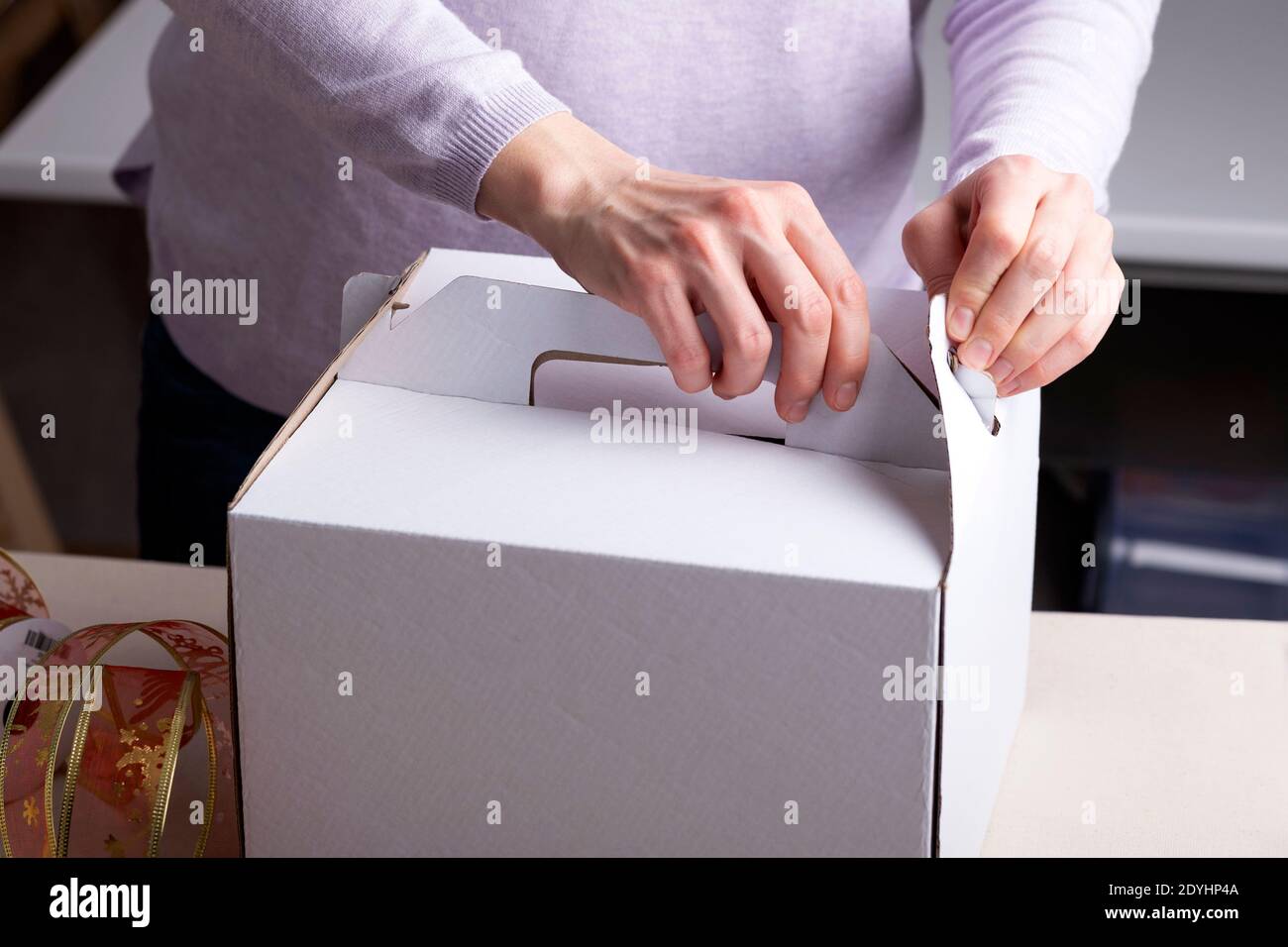 Female hands are wrapping gift in white cardboard box. Confectionery ...