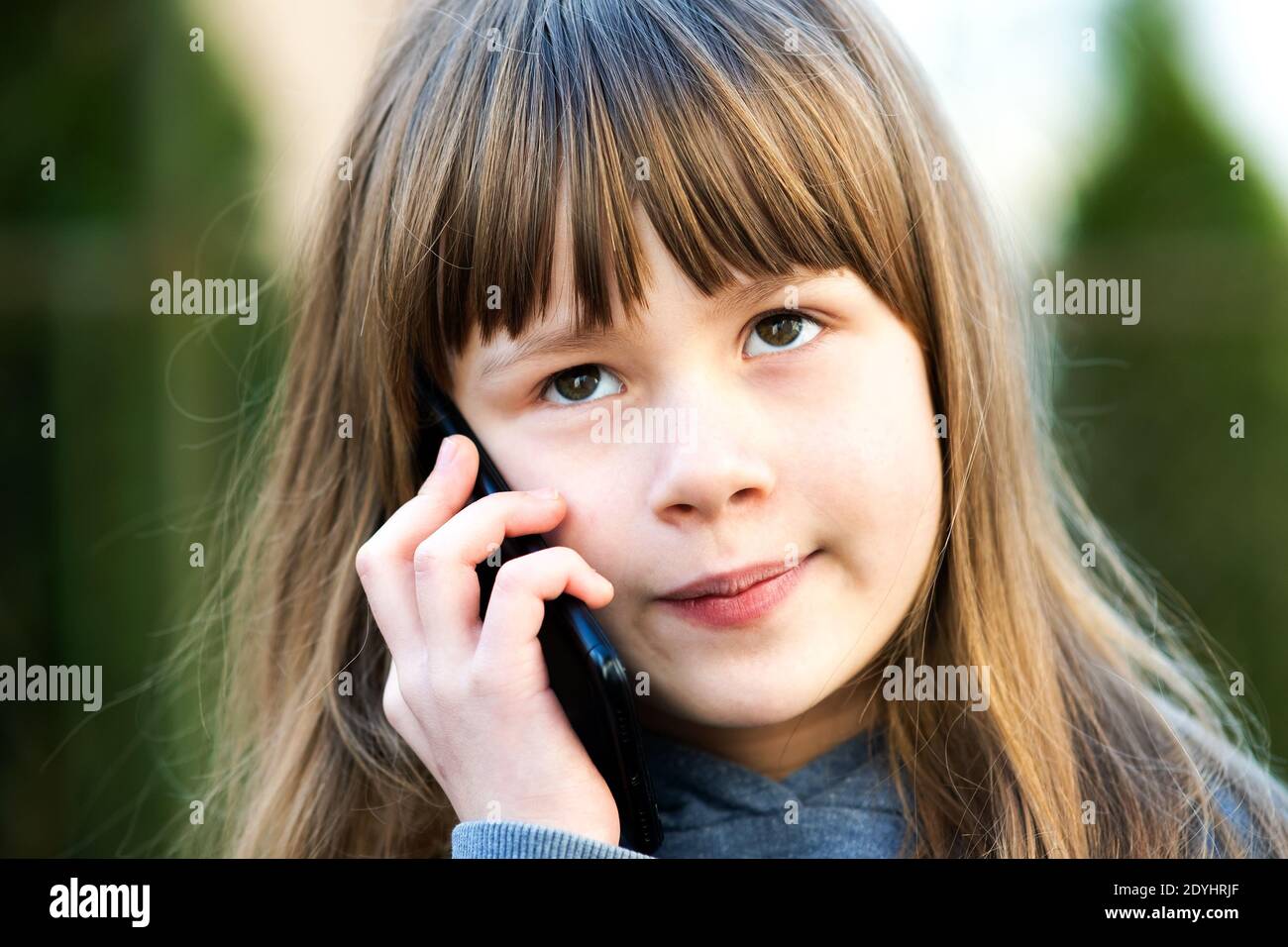 Portrait of pretty child girl with long hair talking on cell phone ...