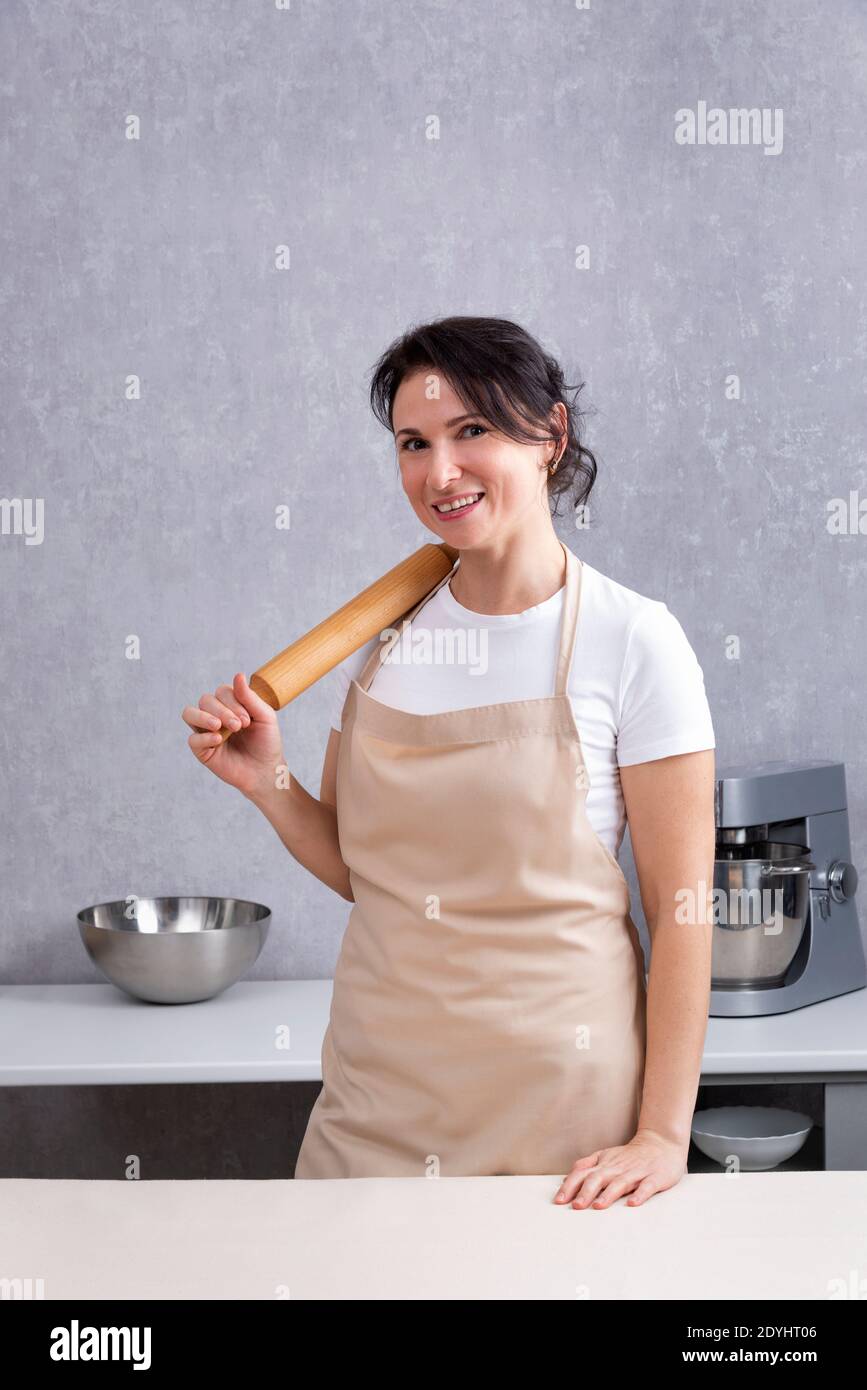 Chef with rolling pin on her shoulder and smiles at the camera ...