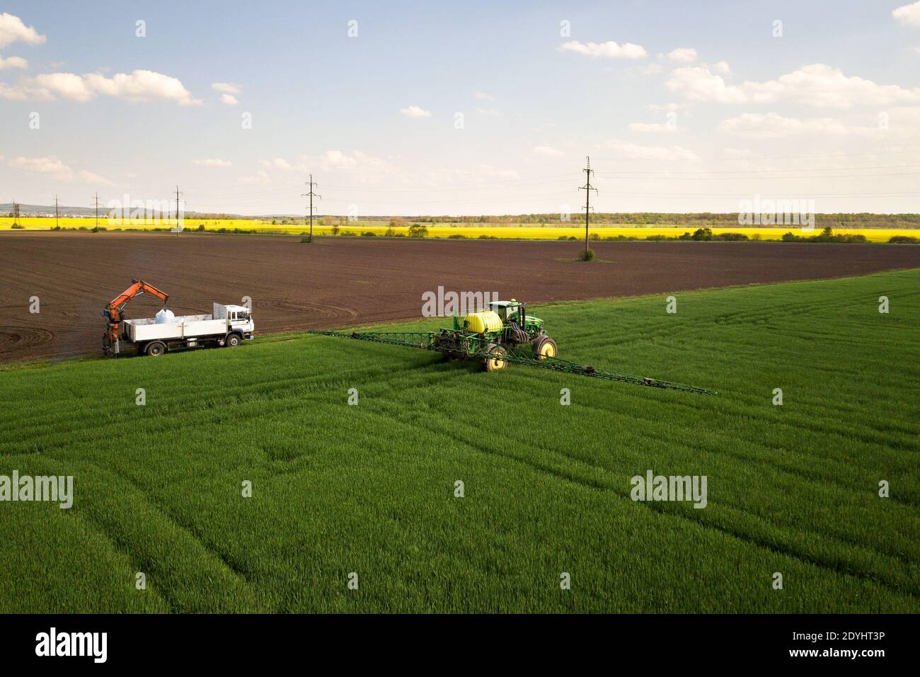Tractor spraying chemical pesticides with sprayer on the large green ...