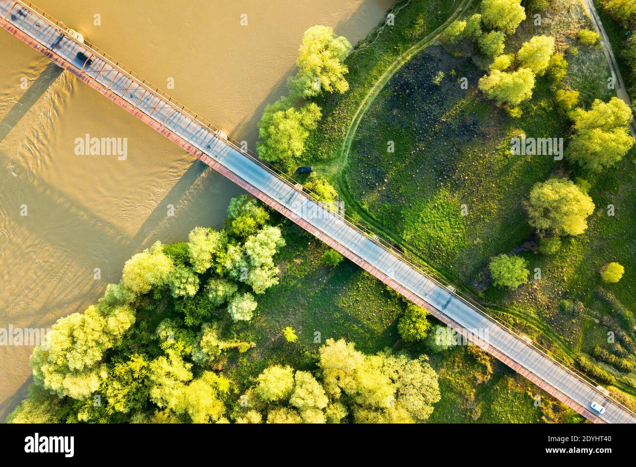 Aerial view of a narrow road bridge stretching over muddy wide river in ...
