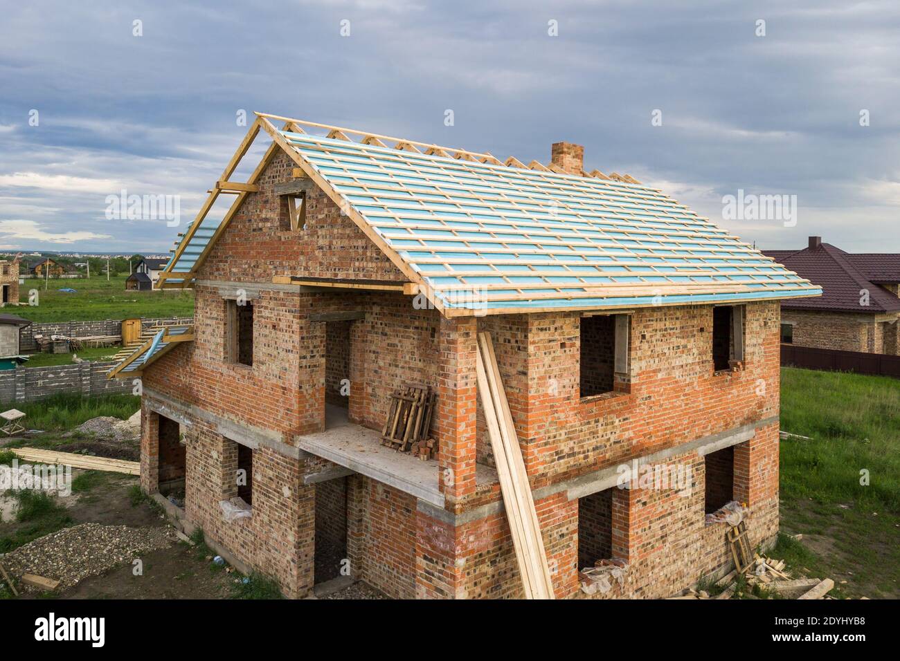 Aerial view of a brick house with wooden roof frame under construction ...