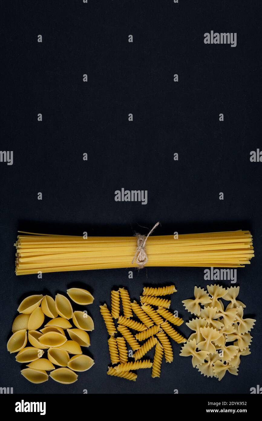 Assorted types of pasta on black background. Top view. Various forms of ...