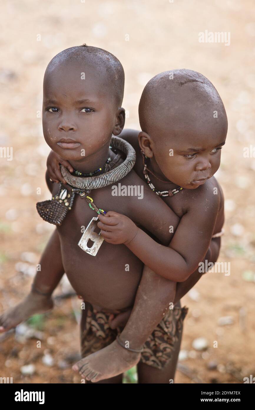 Himba child carrying baby in village, Kaokoland, Namibia Stock Photo ...