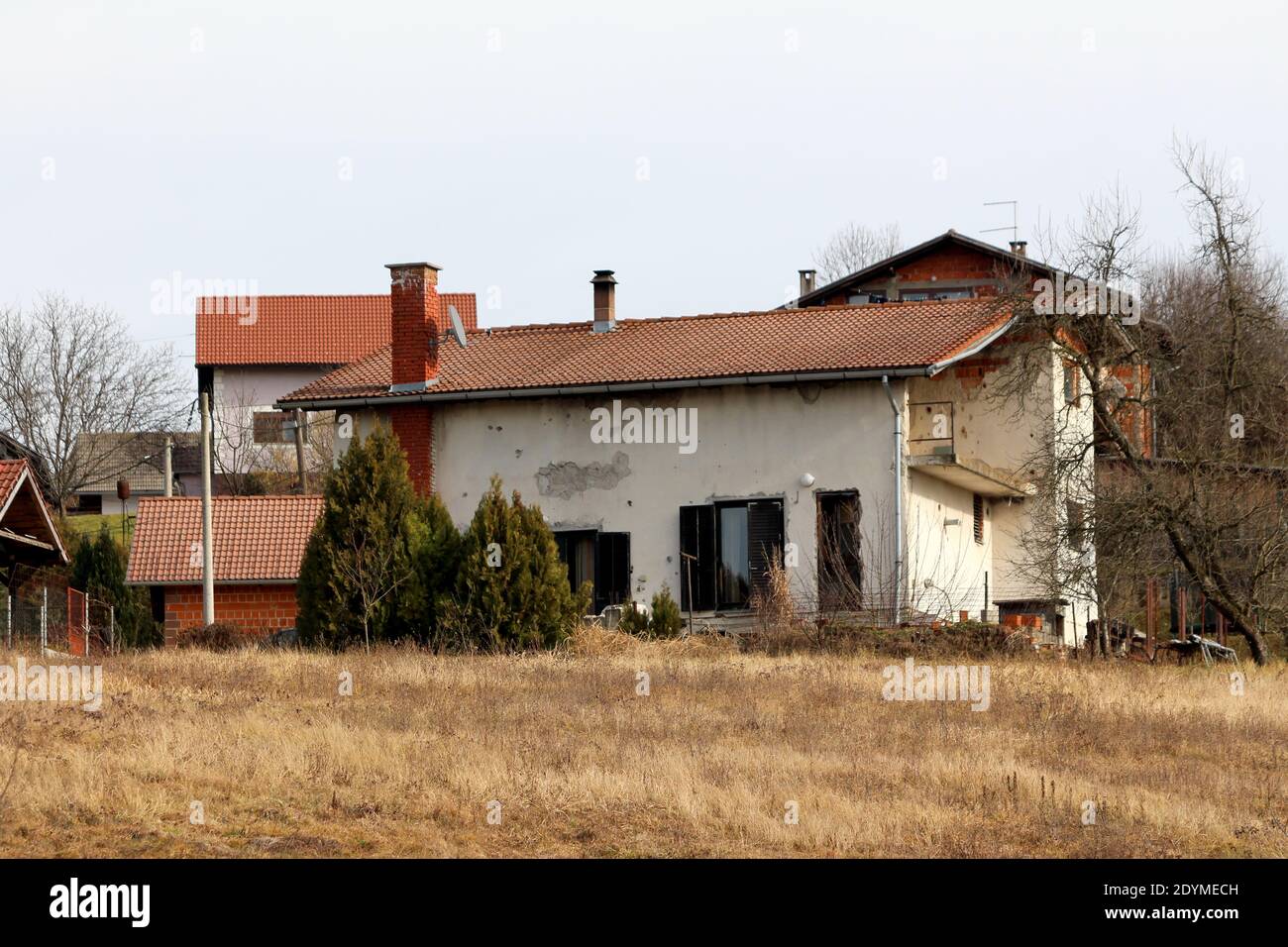 White suburban family house damaged by shrapnel during war with dilapidated facade and repaired ...