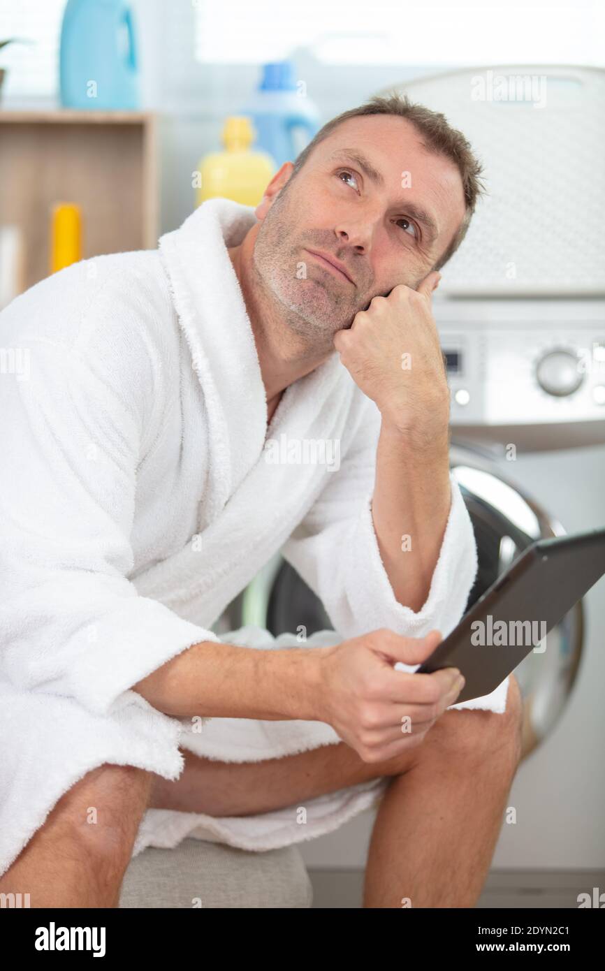 pensive man wearing bathrobe doing laundry Stock Photo - Alamy