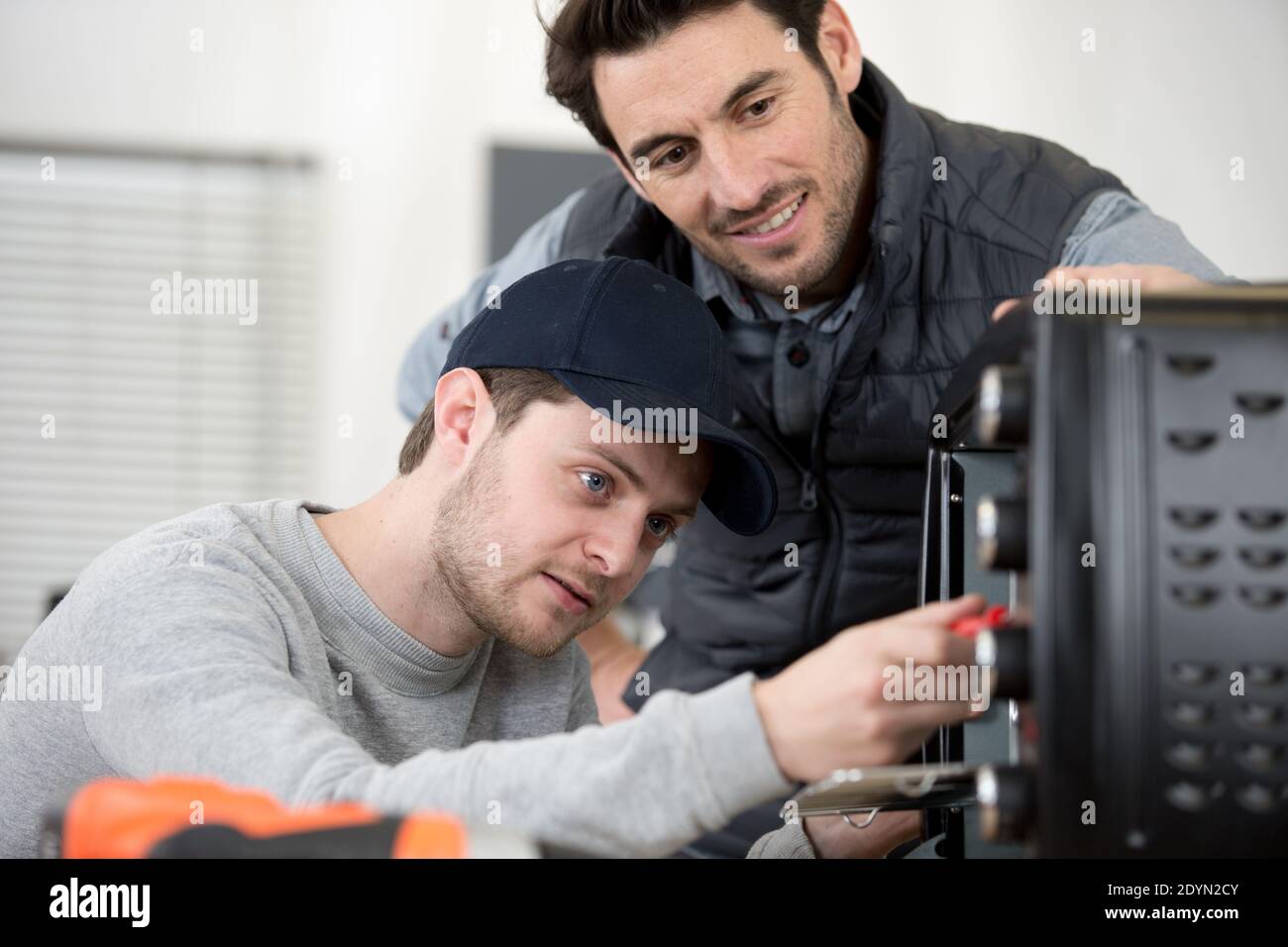 expert and apprentice fixing the kitchen oven Stock Photo - Alamy