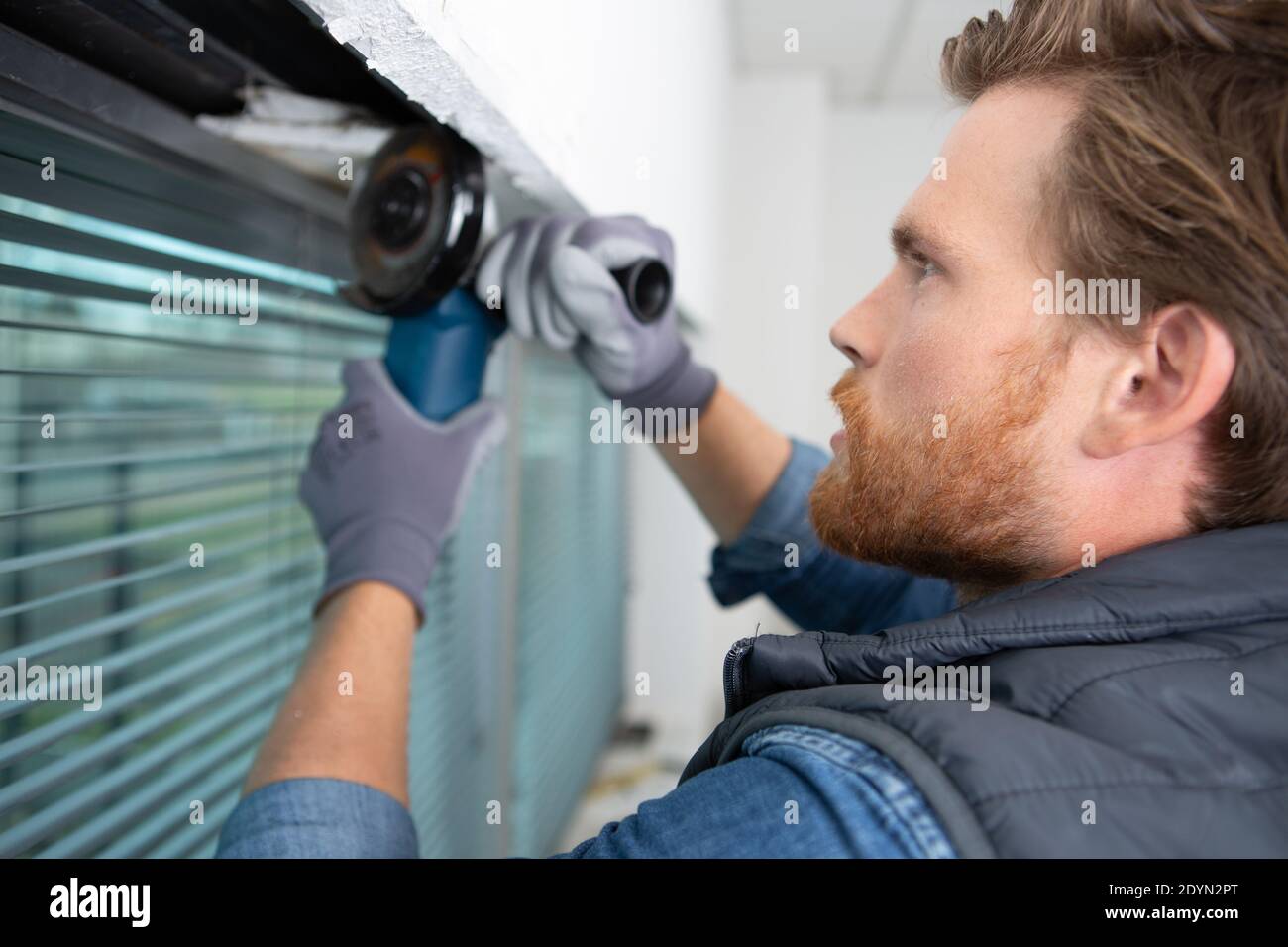 man fixing metal frame using angle grinder on windows Stock Photo - Alamy