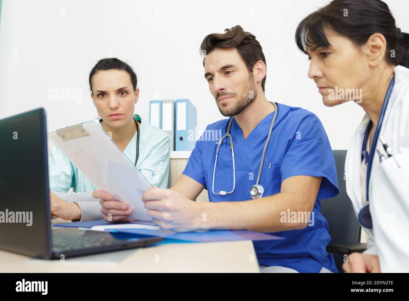 medical staff sat at desk reading notes on clipboard Stock Photo - Alamy