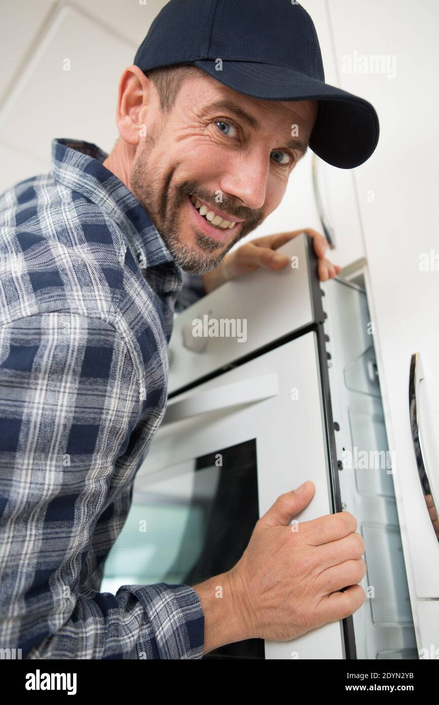 happy man installing an oven in a fitted kitchen Stock Photo - Alamy