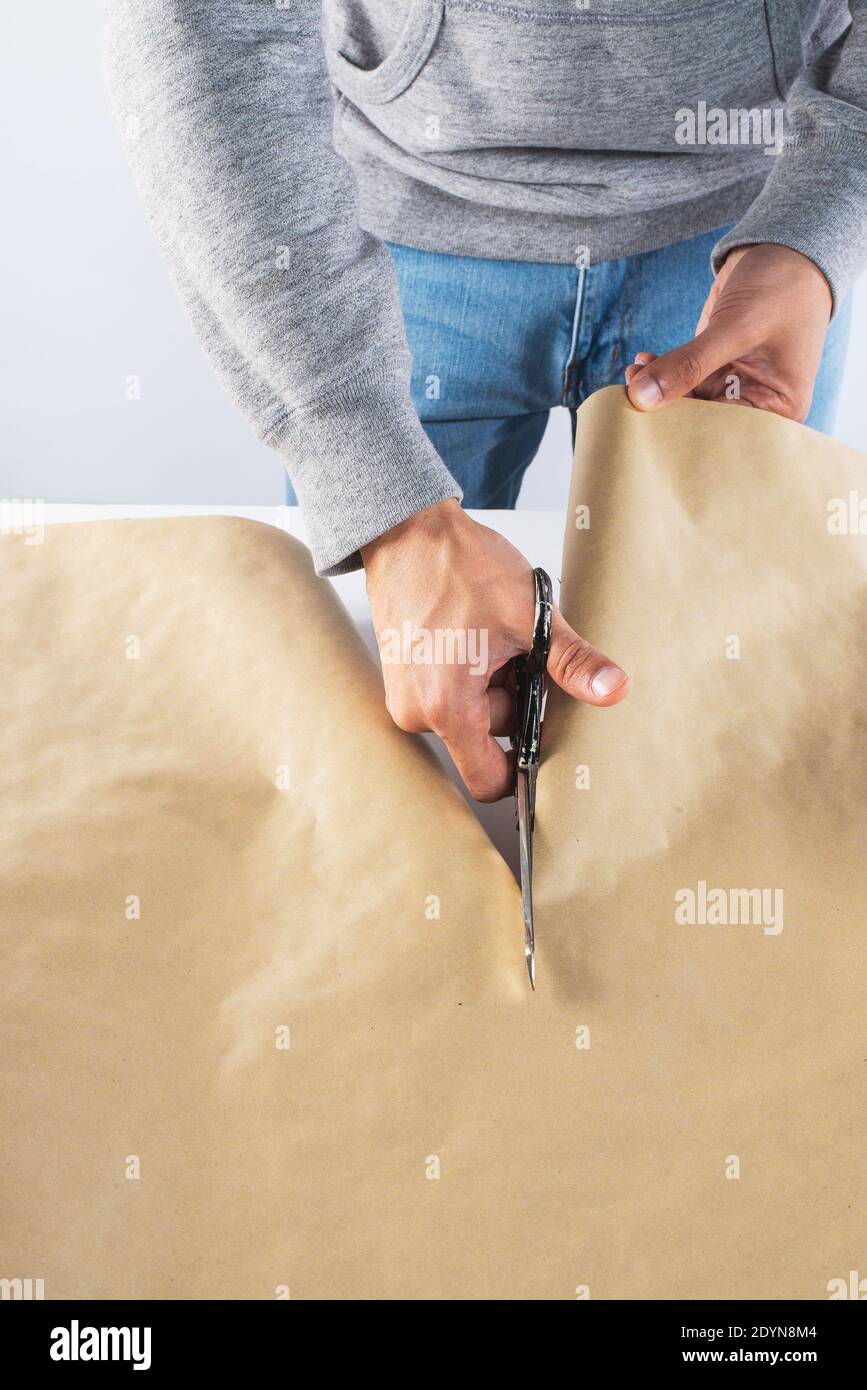 a person carefully cuts through kraft paper Stock Photo - Alamy