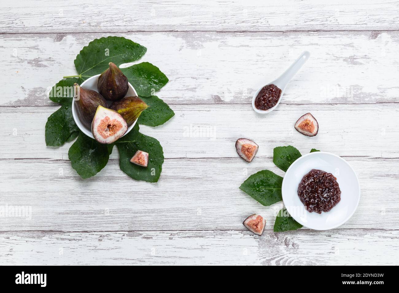 Fig jam with figs, fig leaves and white spoon with jam on White wood ...