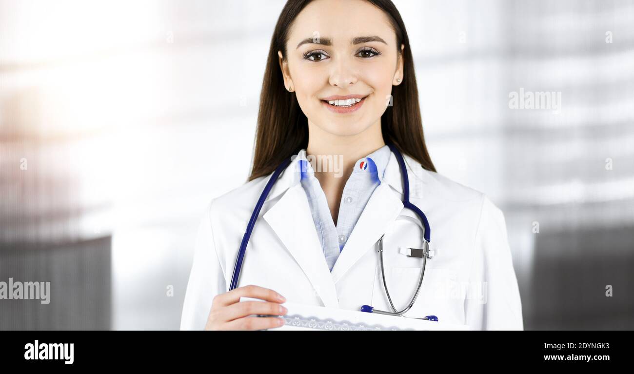 Happy young woman-doctor is holding a certificate in her hands ...