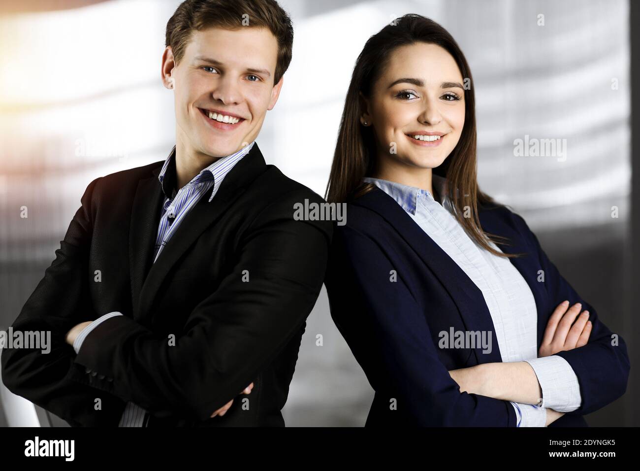 Friendly young colleagues are standing as a team with crossed arms in ...