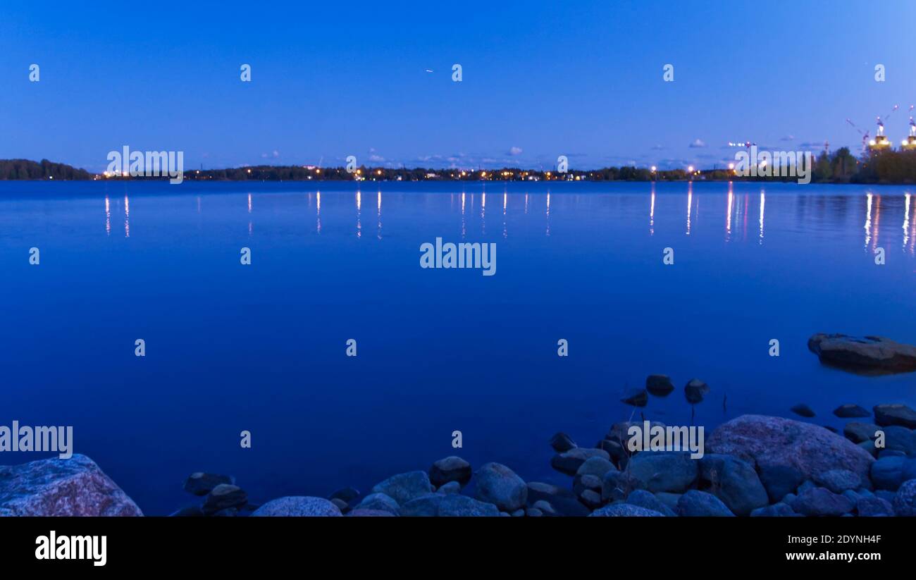 Blue sky and lake; night lights reflecting on the lake Stock Photo - Alamy