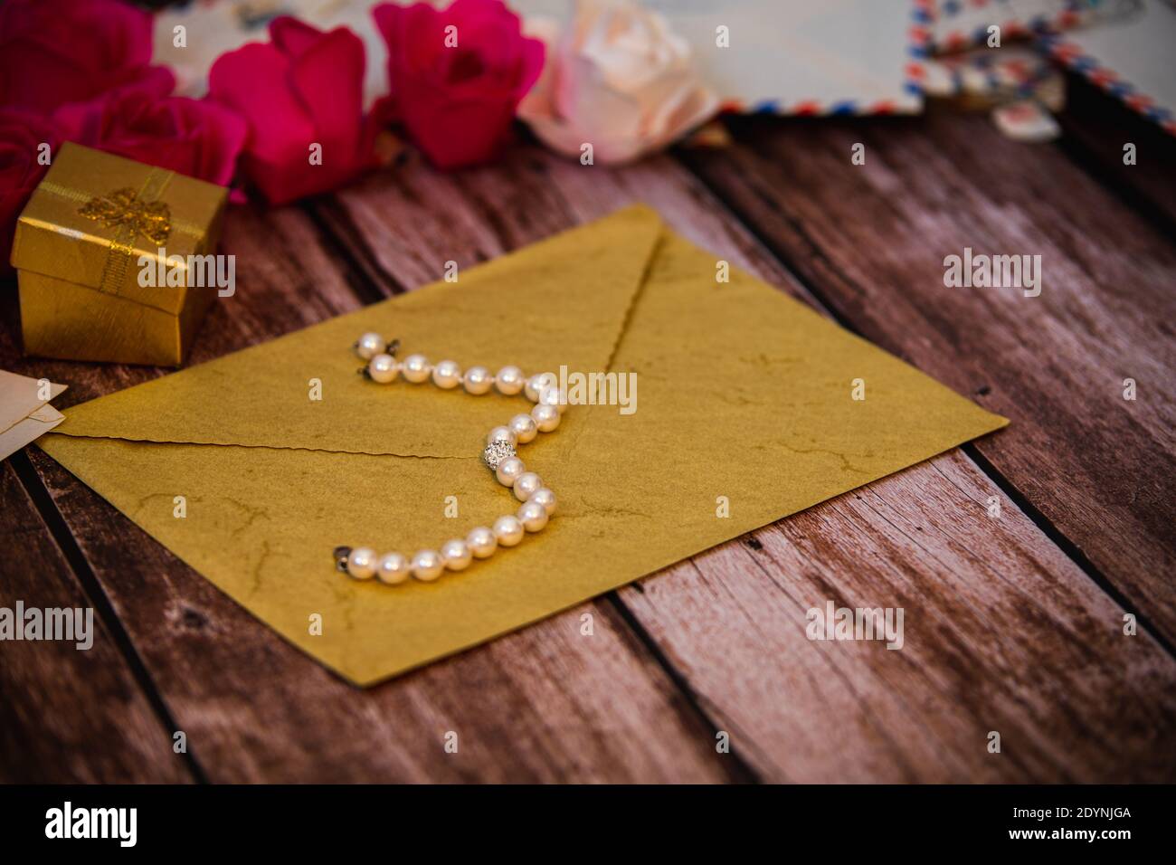 closed envelope with a pearl necklace on top and a gift box in the ...