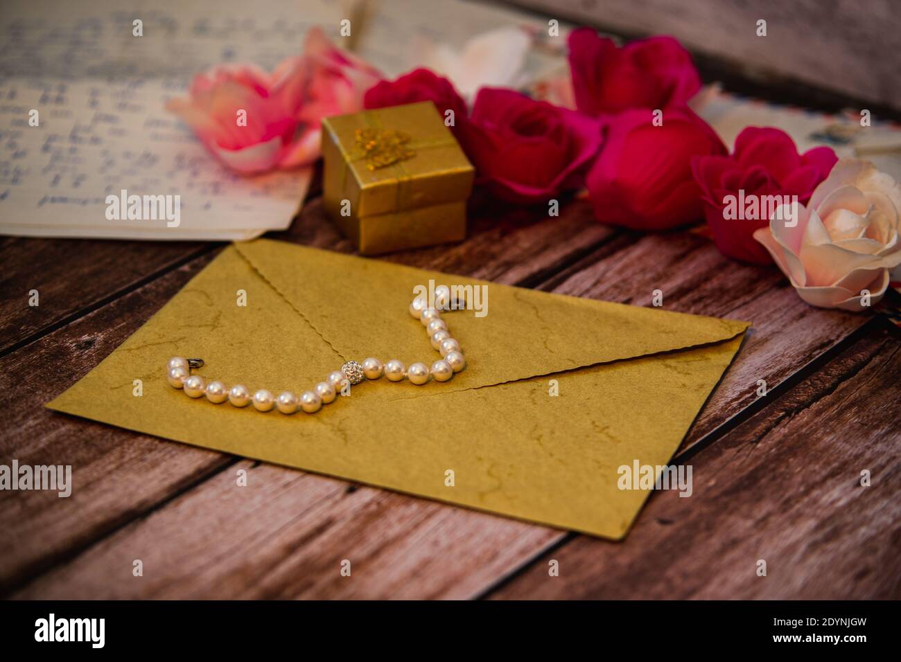 closed envelope with a pearl necklace on top and a gift box in the ...