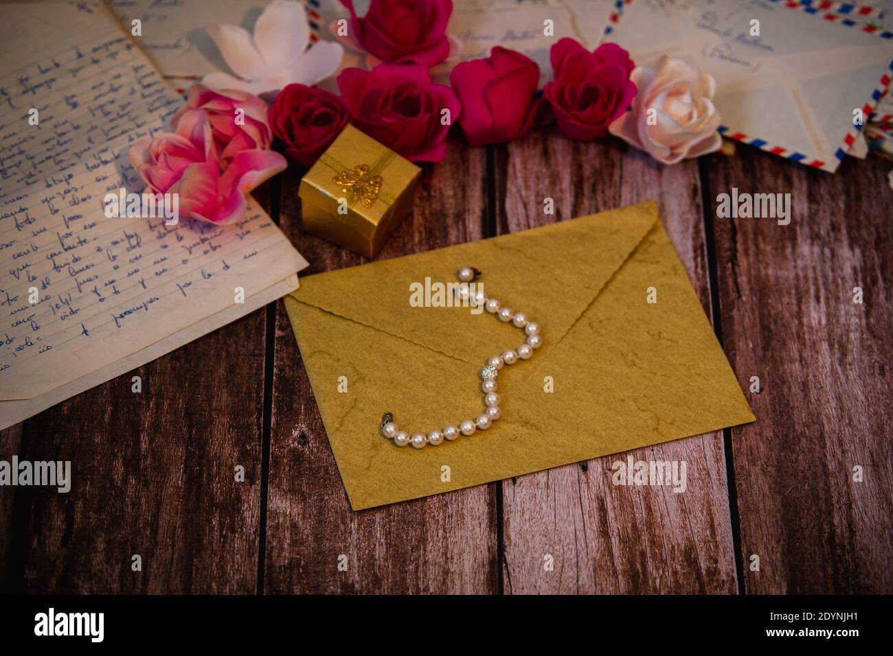 closed envelope with a pearl necklace on top and a gift box in the ...