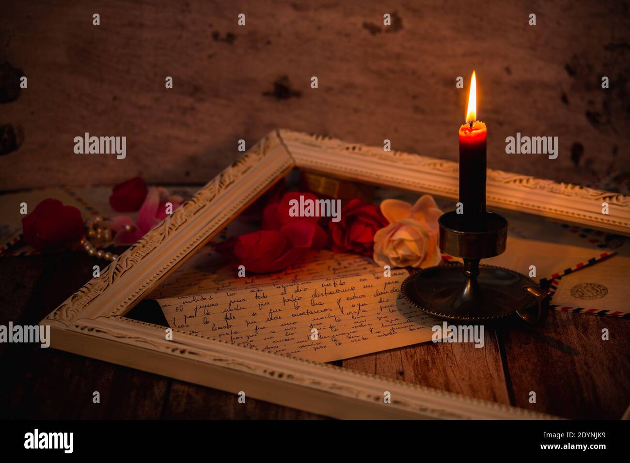 Envelopes with romantic letters inside them lit by a candle on wooden ...