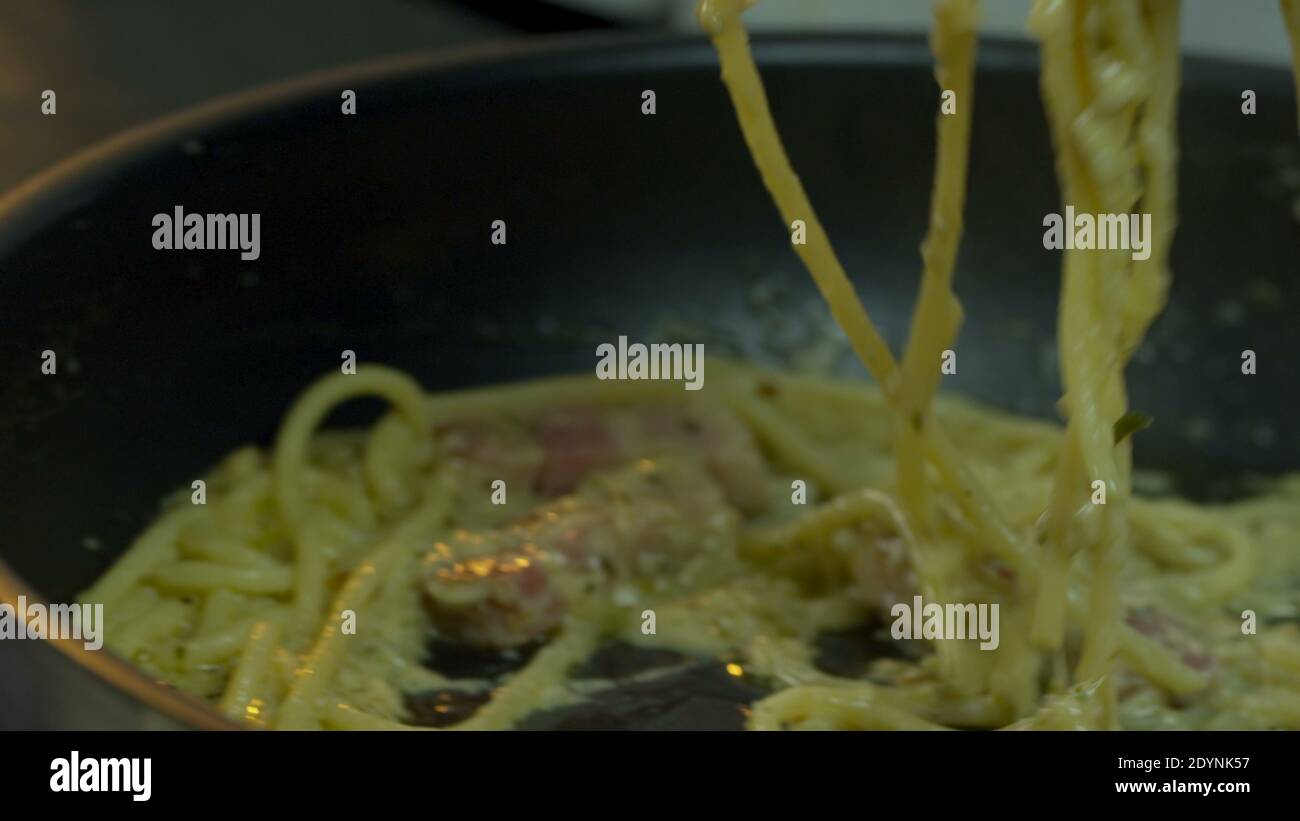 Chef Adds Spaghetti from Frying Pan to Plate Stock Photo - Alamy