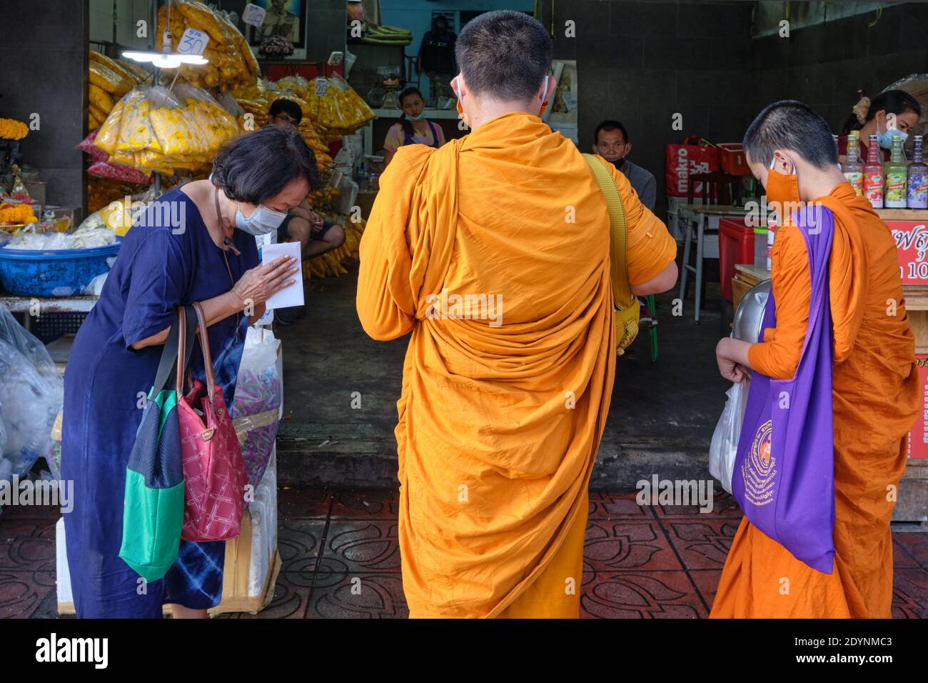A Thai woman bowing and asking for blessings fro two young Buddhist ...