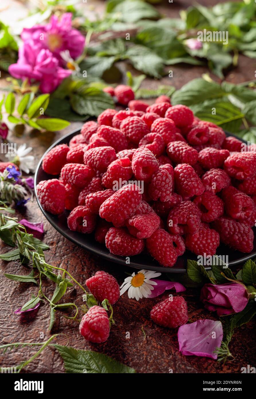 Fresh juicy raspberries on a black plate. Summer still life with ...