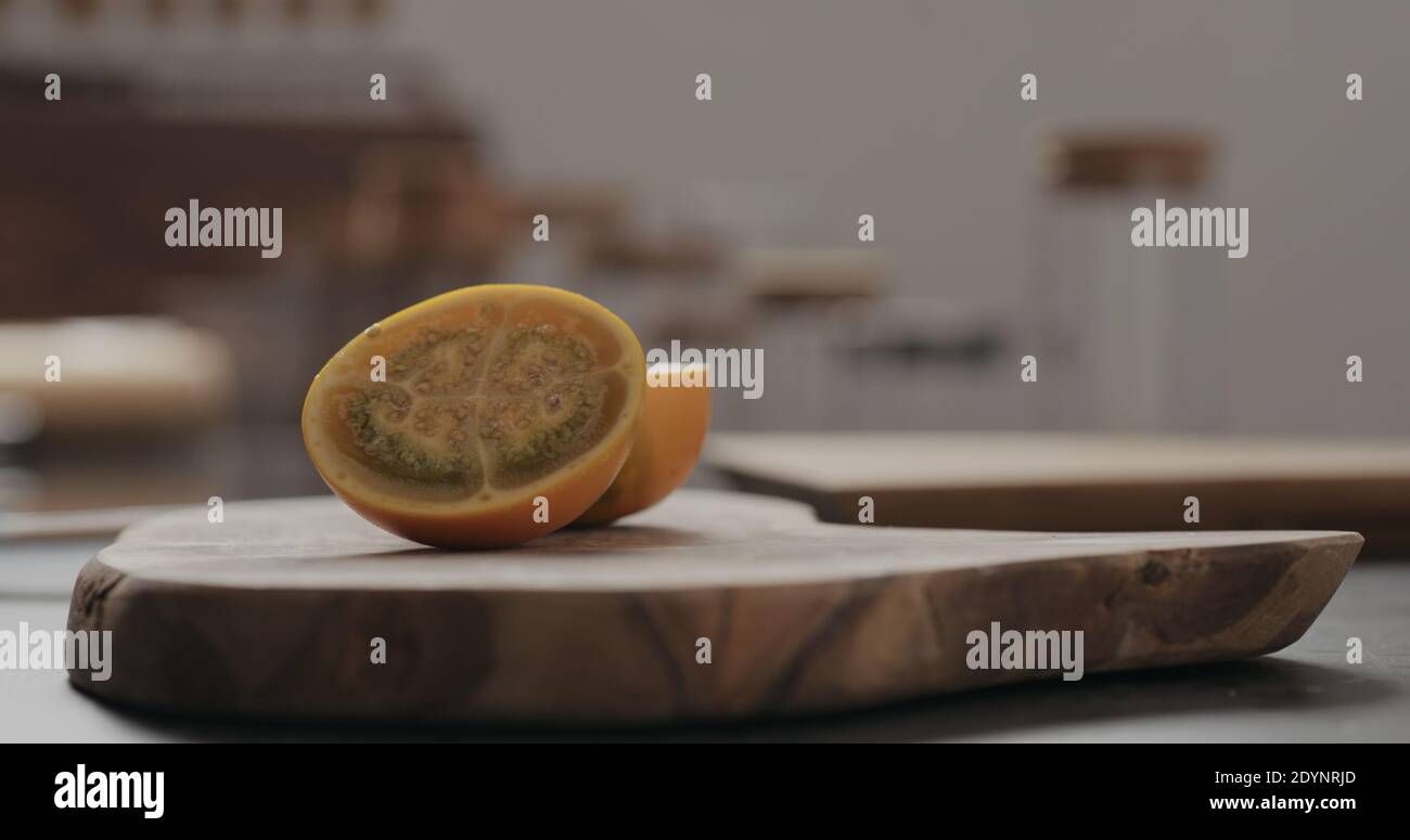 cut in halves lulo fruit on olive wood board with copy space, wide ...
