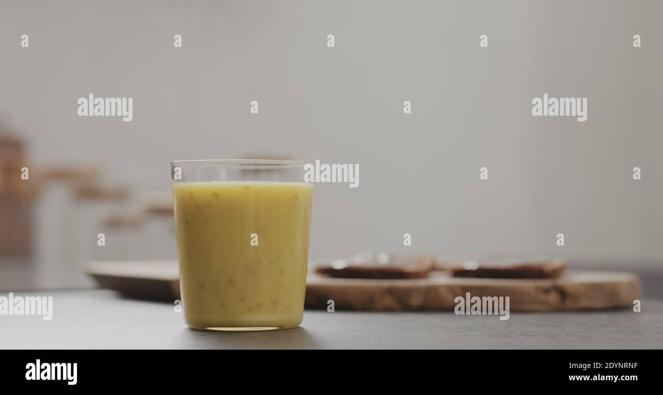 mango lulo smoothie into tumbler glass on concrete countertop with copy ...