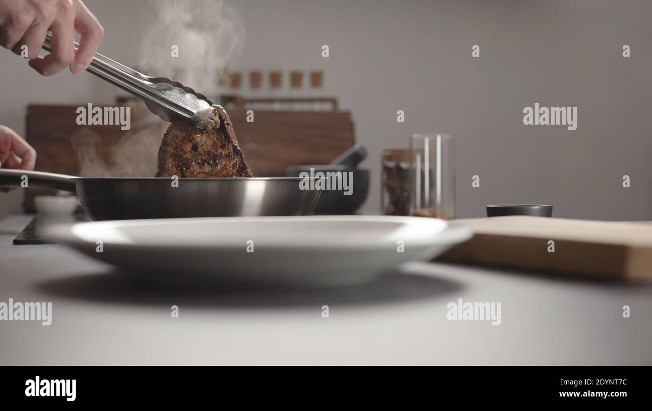 Man hand put cooked steak on white plate for resting before serving ...