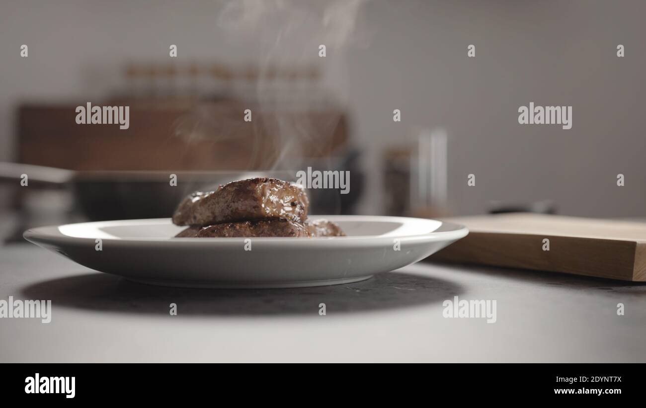 Man hand put cooked steak on white plate for resting before serving ...