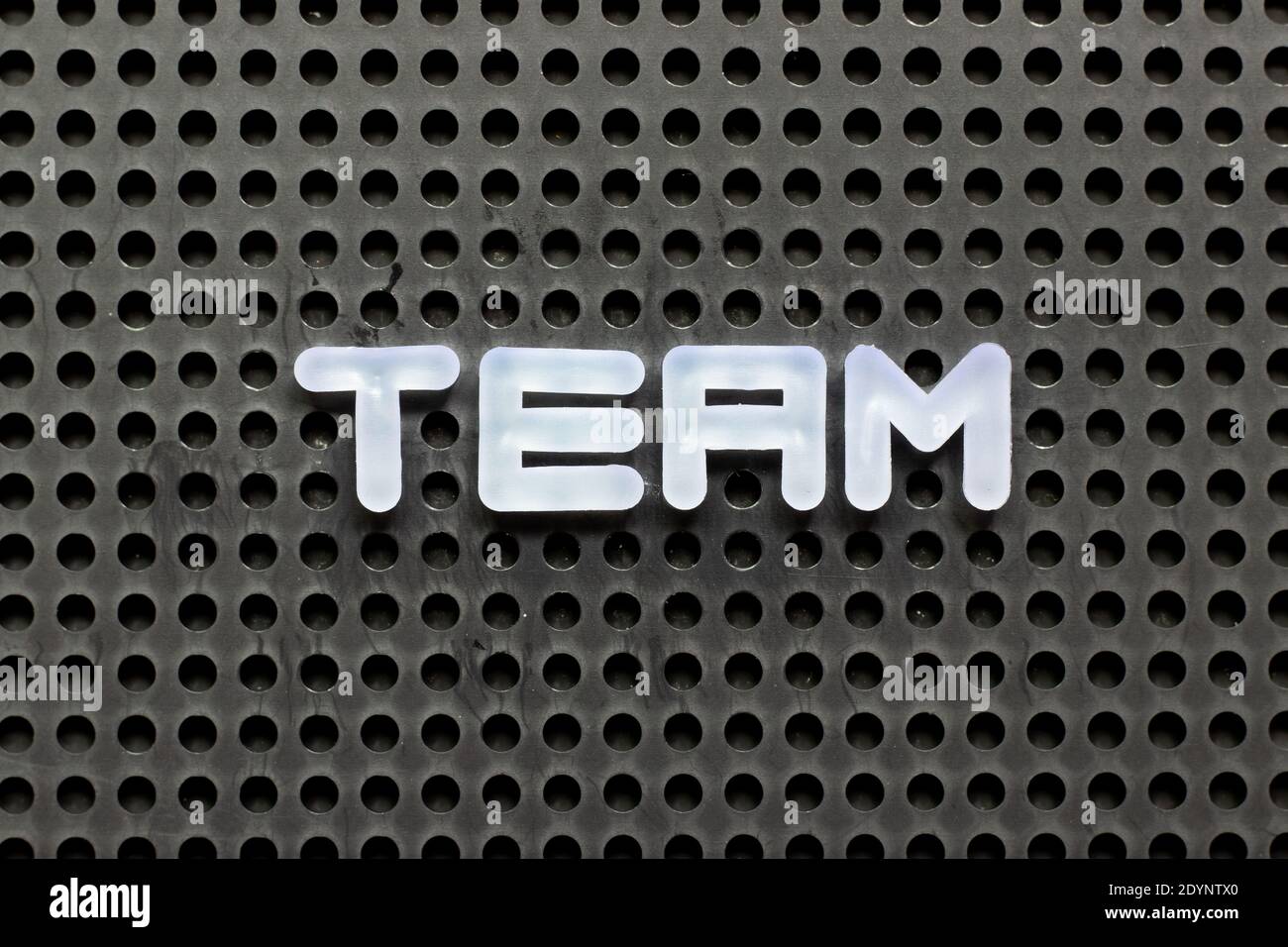 White color letter in word team on black pegboard background Stock ...