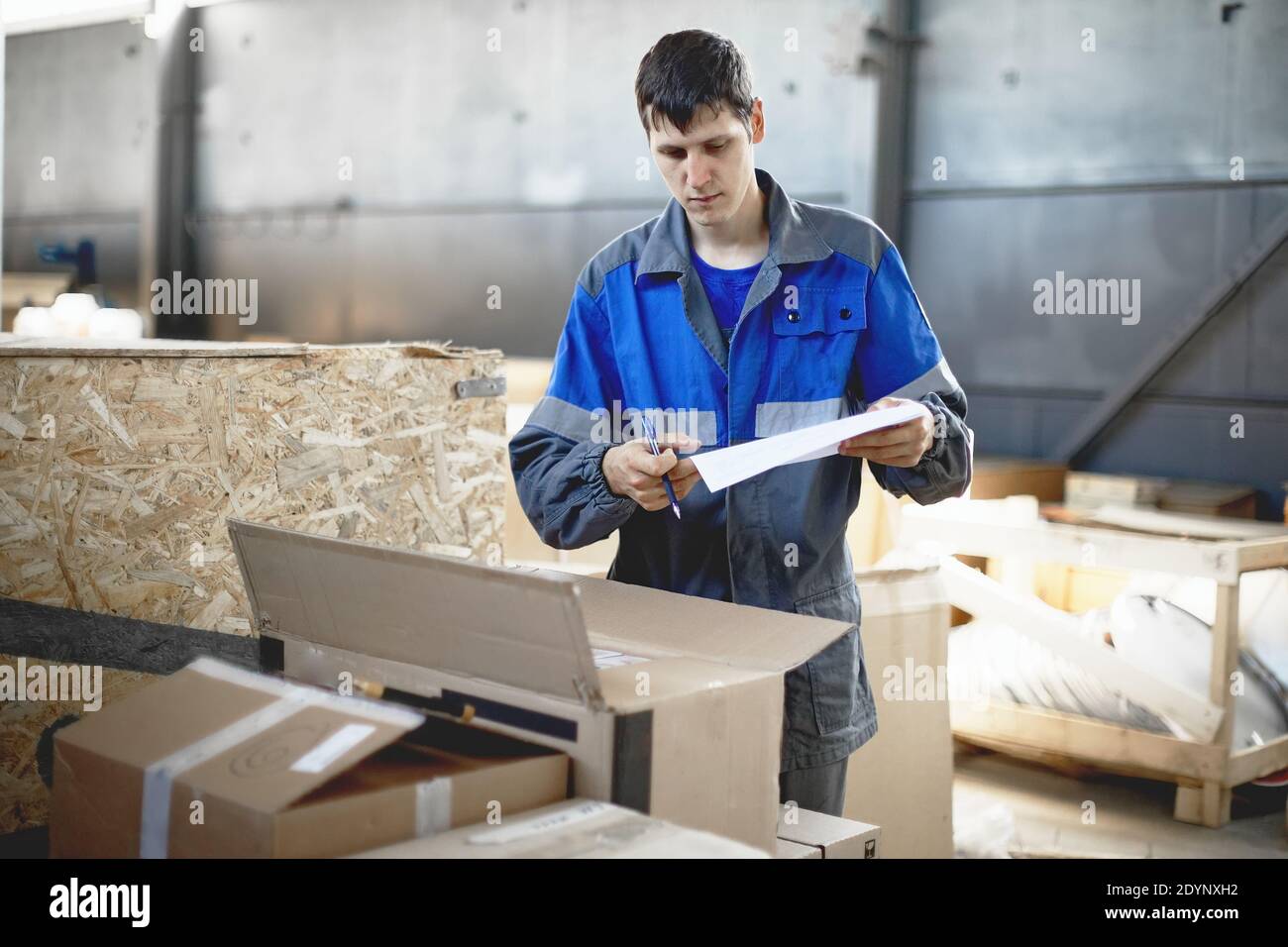 Acceptance of goods in the warehouse. A young worker in overalls checks ...