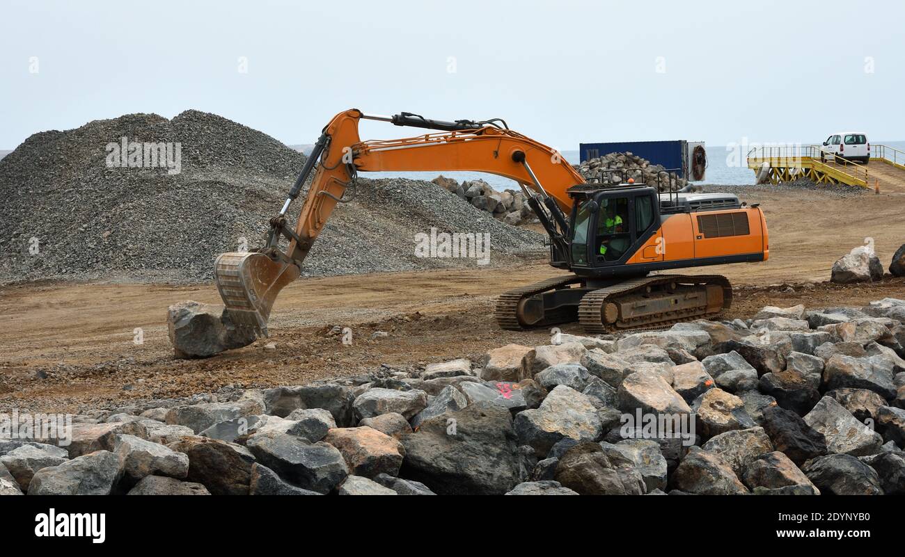 Digger moving large boulders on construction site Stock Photo - Alamy